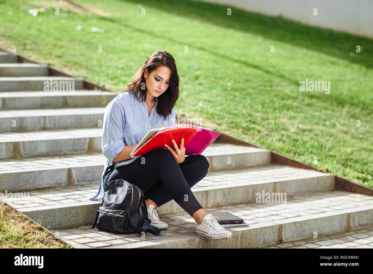 Student sitting on stairs outdoors taking notes in a notebook Stock ...