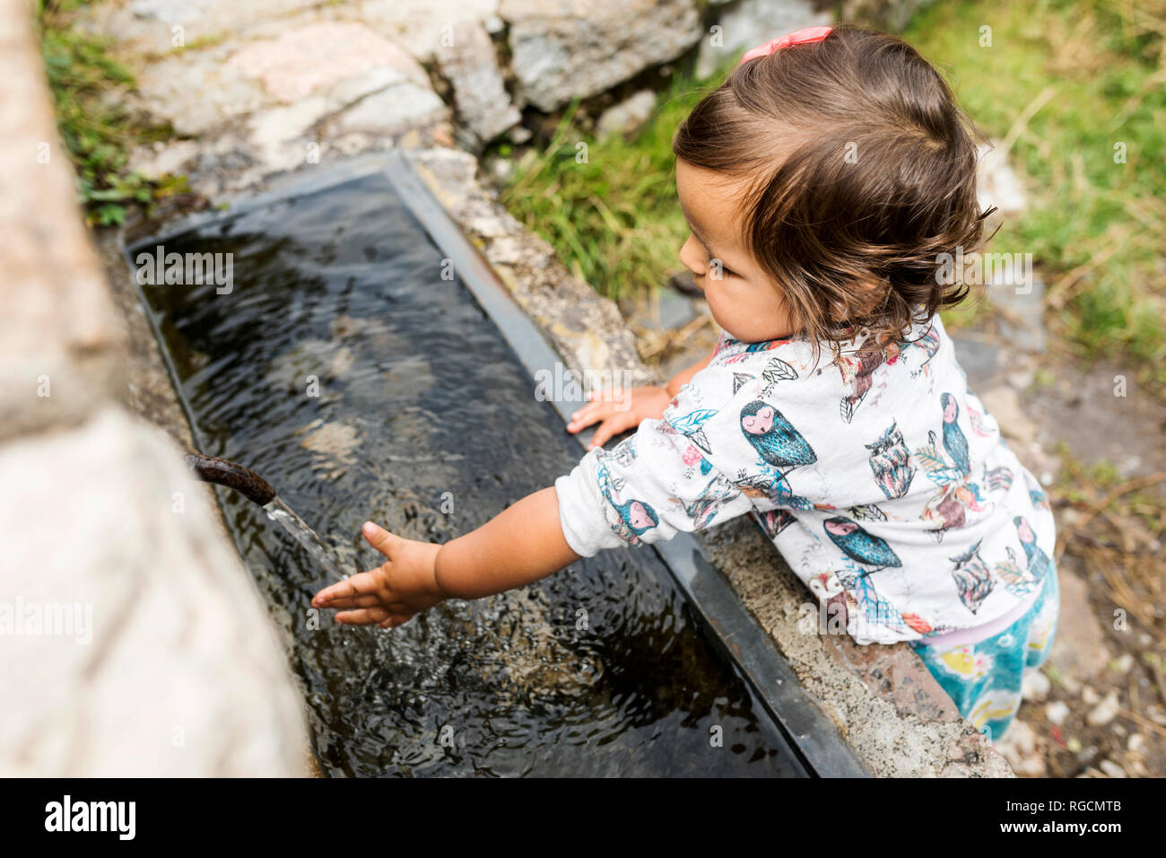 Baby girl splashing with water at well Stock Photo - Alamy