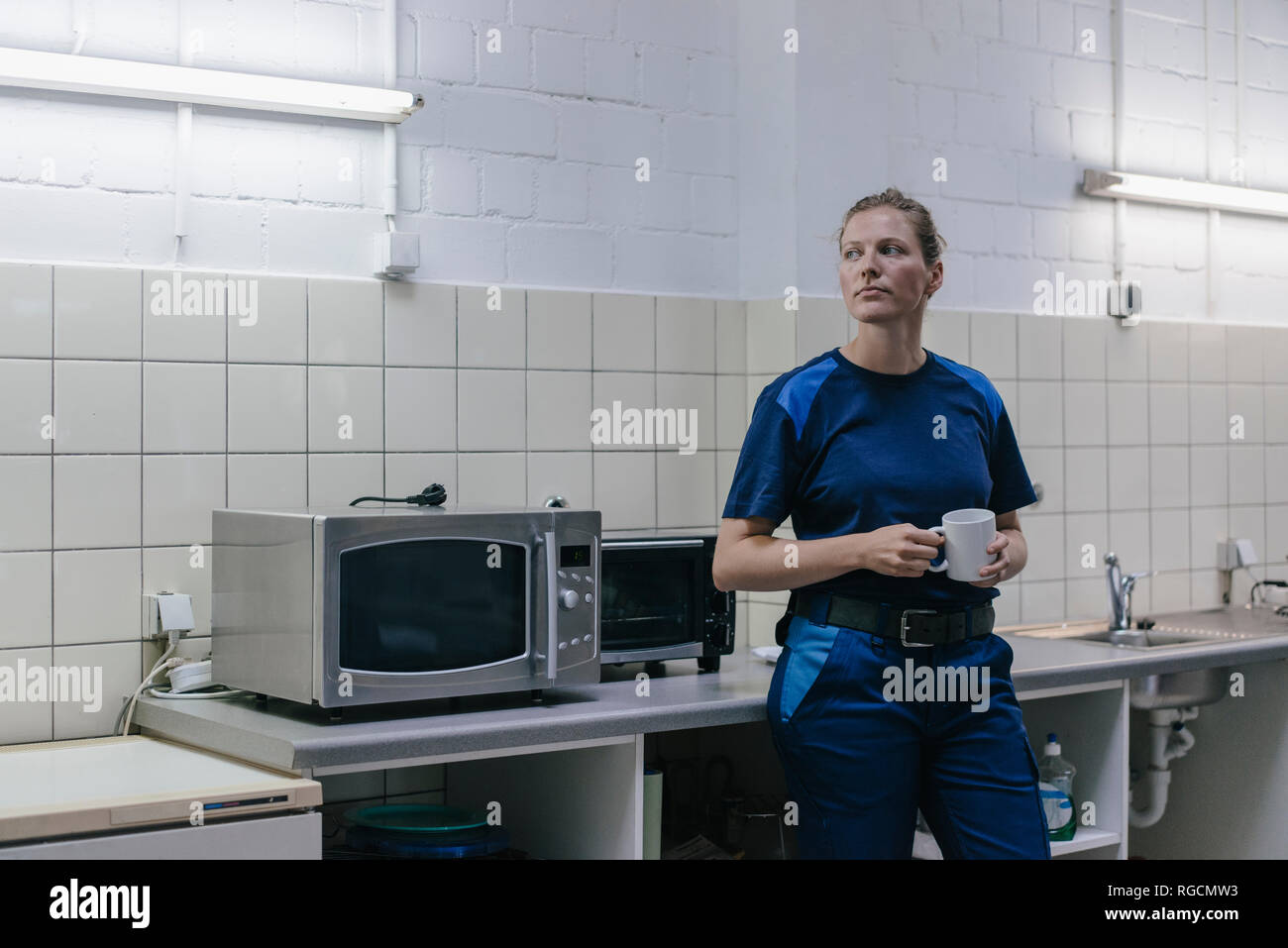 Young woman working in high tech enterprise, taking a break, drinking ...