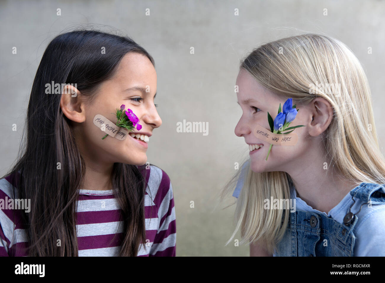 Two smiling girls with flower heads on their cheeks Stock Photo - Alamy