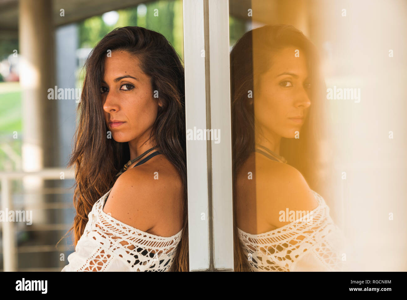 Portrait of young woman leaning against a window Stock Photo - Alamy
