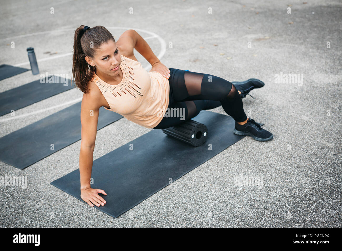 Young woman doing side plank exercise with fascia roll outdoors Stock ...