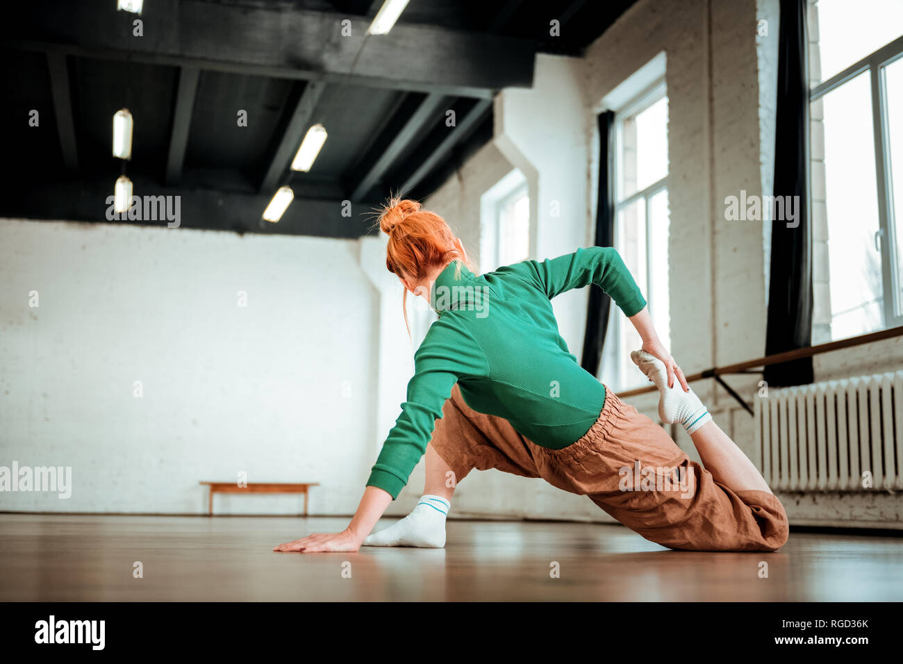 Professional yoga coach with a hair bun stretching her leg Stock Photo ...