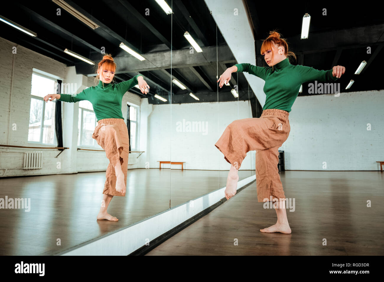 Pretty red-haired professional dancer in a green turtleneck looking ...