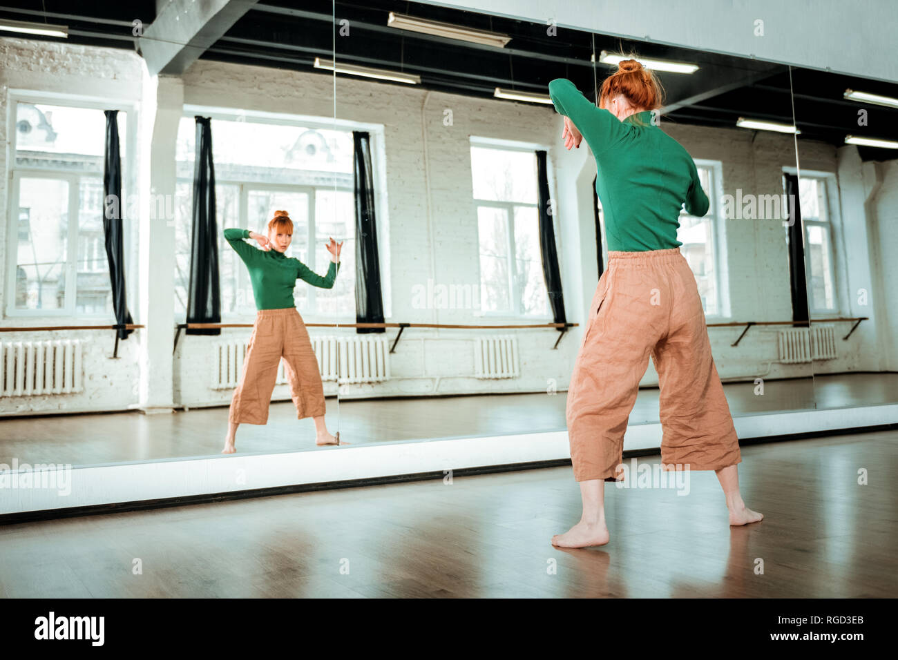 Young red-haired dance teacher with a hair bun spending her day in the ...