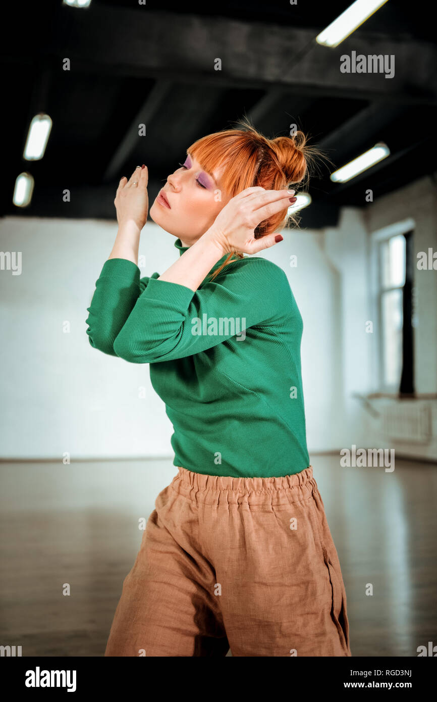 Red-haired professional choreographer in a green turtleneck dancing ...