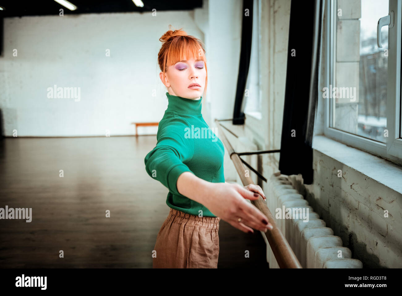 Red-haired professional ballet dancer with hair bun looking focused ...
