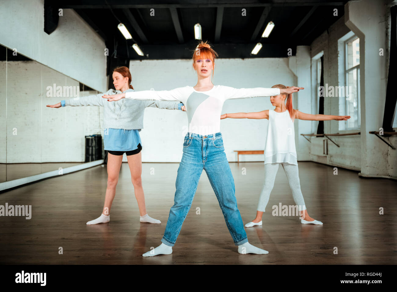 Slim beautiful ballet teacher conducting a lesson for two teenagers ...