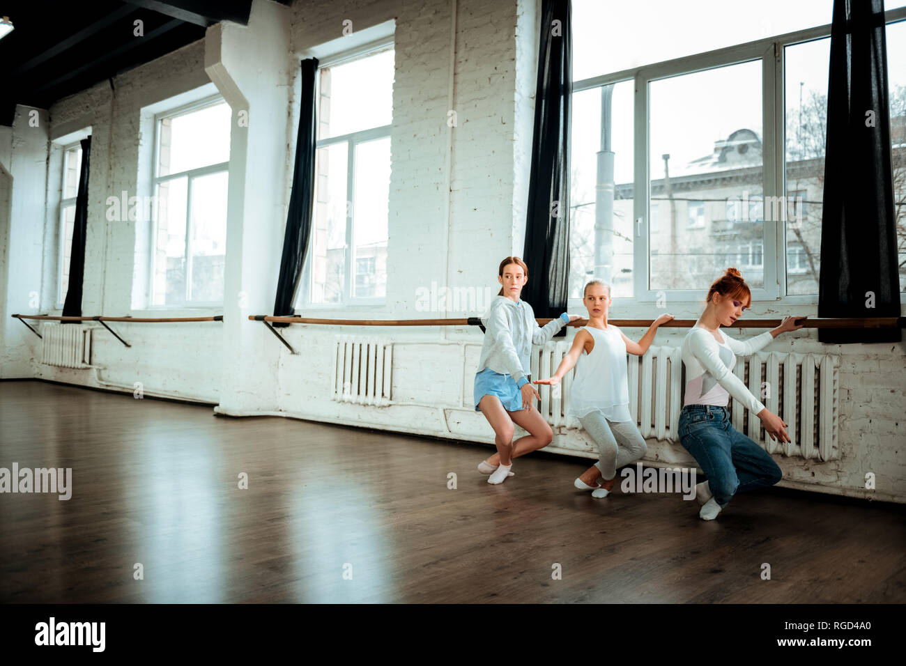 Red-haired ballet teacher and her students squatting in the third ...