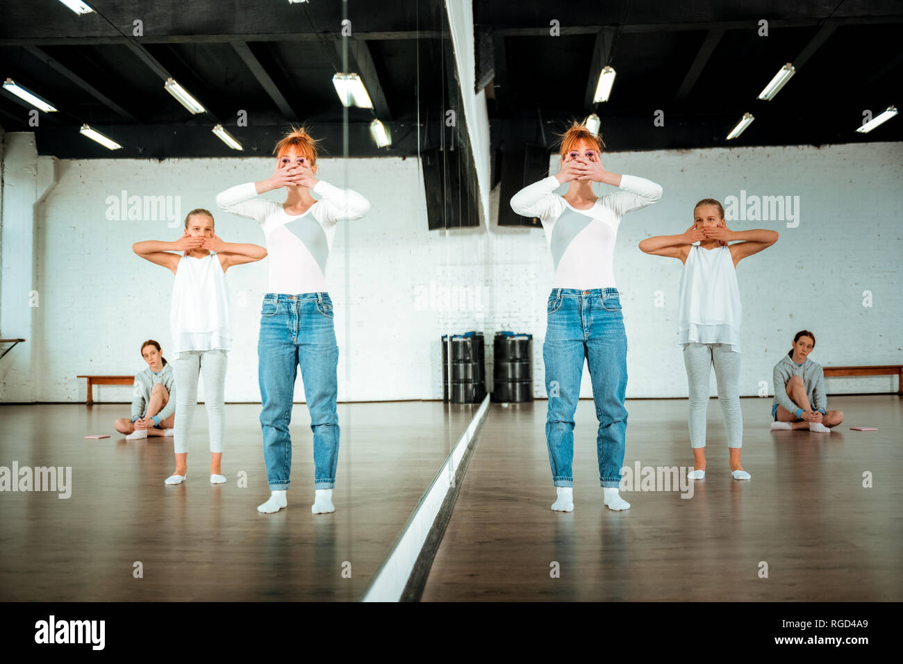 Red-haired ballet teacher and her students practicing elements of ...
