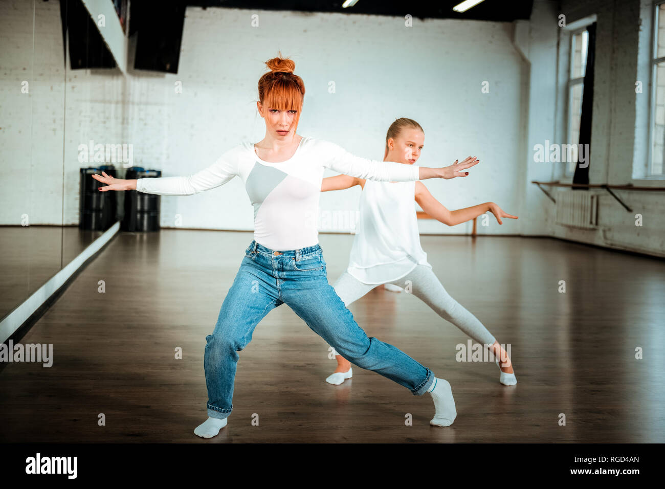 Red-haired ballet teacher and her student practicing in the dance ...