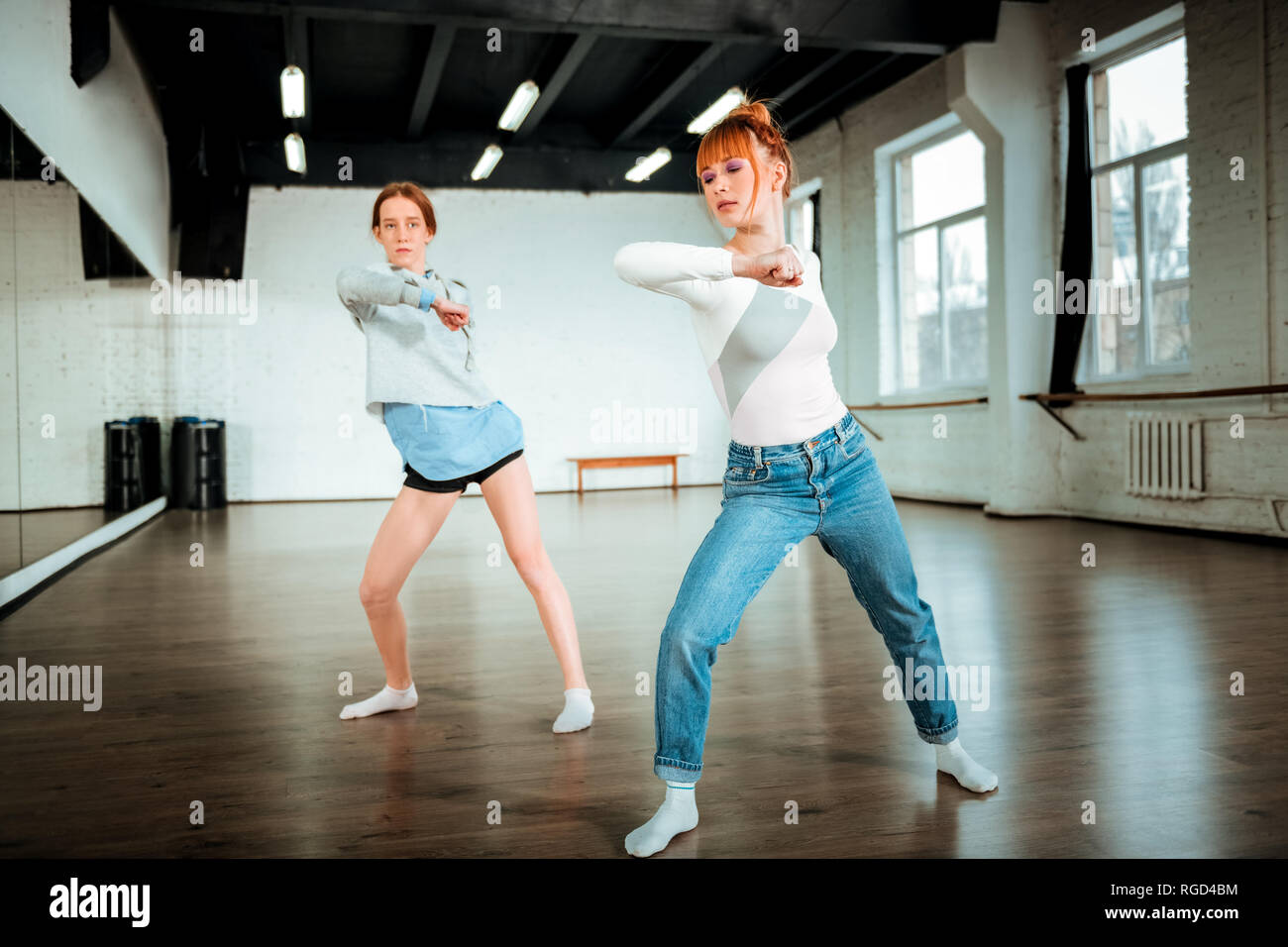 Beautiful red-haired professional dancer in blue jeans and her student ...