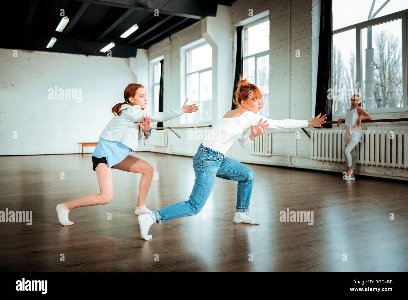 Beautiful red-haired professional dancer in blue jeans and her student ...