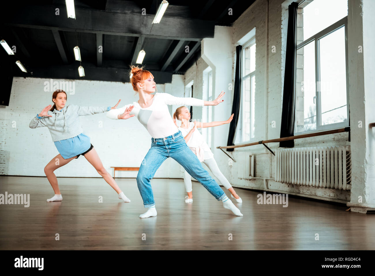 Red-haired dance teacher in blue jeans and her students dancing in the ...