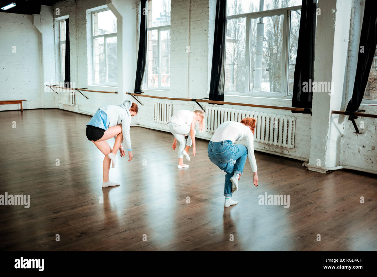Red-haired dance teacher in blue jeans and two students looking ...