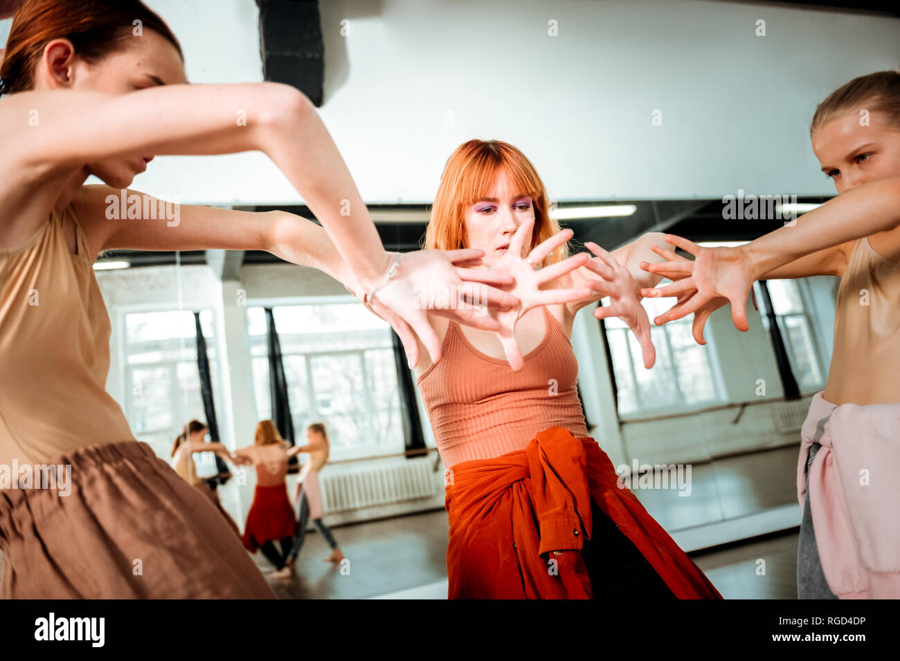 Beautiful dance teacher with red hair explaining moves to her students ...