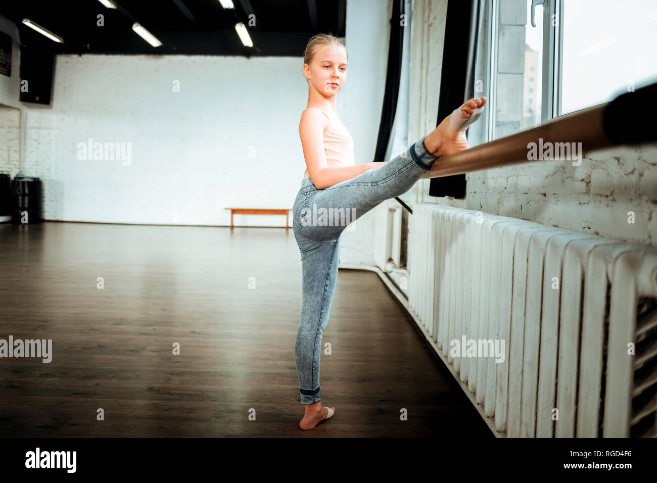 Beautiful blond teenager from generation z stretching her leg near the ...