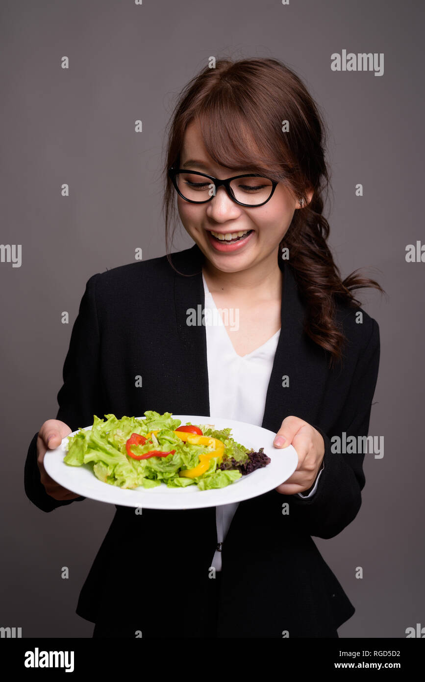 Happy Asian businesswoman holding salad while smiling Stock Photo - Alamy