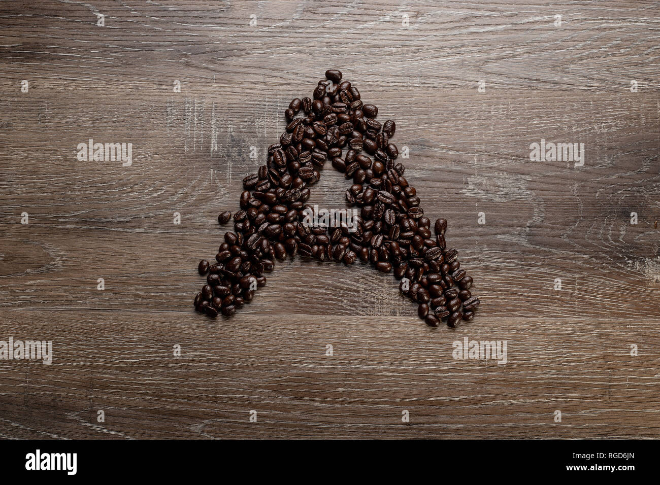 Dark roasted coffee bean arranged on a wooden table in the shape of ...