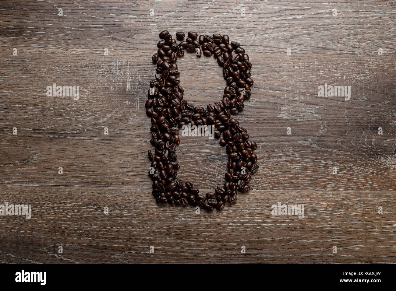 Dark roasted coffee bean arranged on a wooden table in the shape of ...