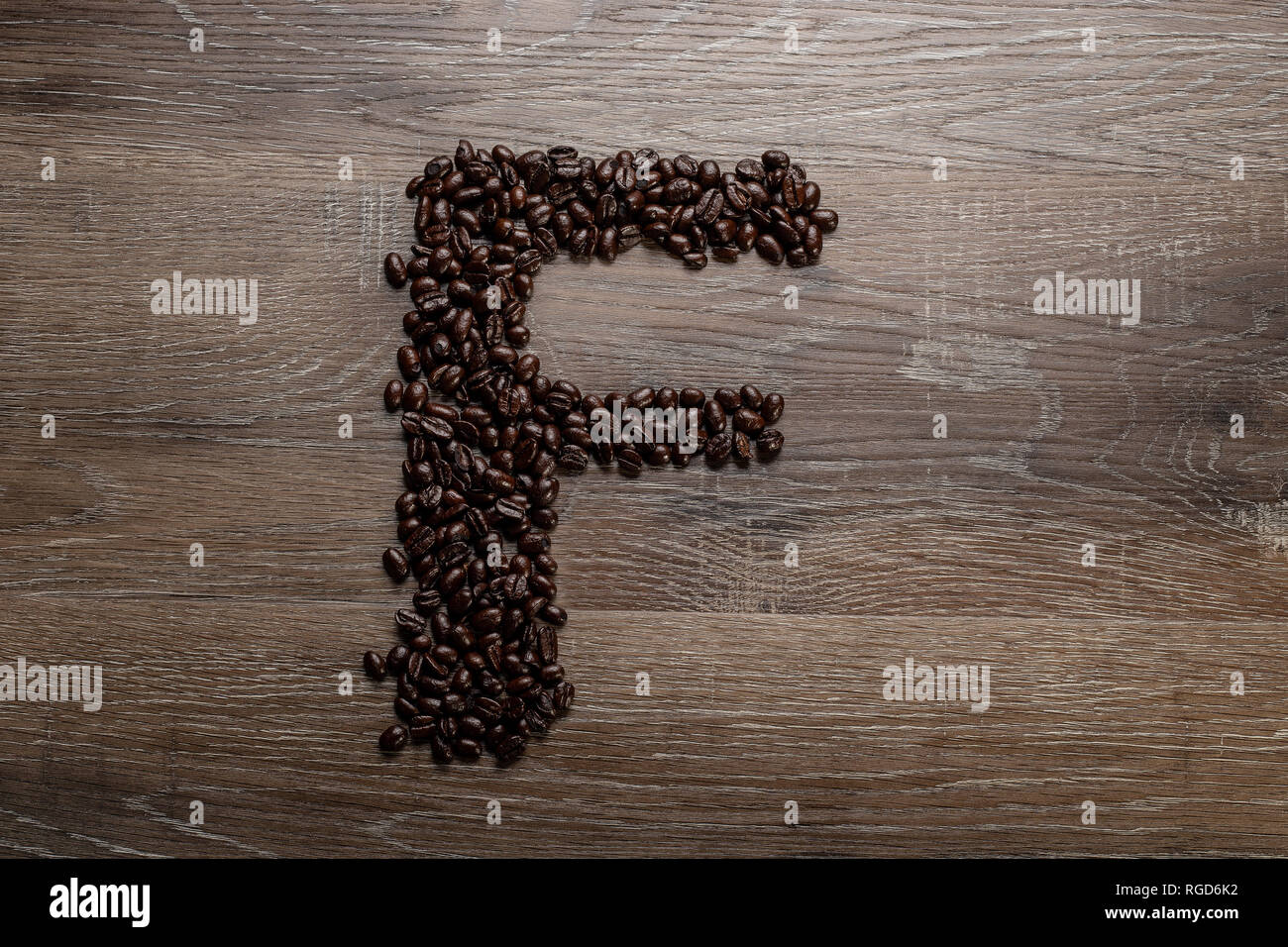 Dark roasted coffee bean arranged on a wooden table in the shape of ...