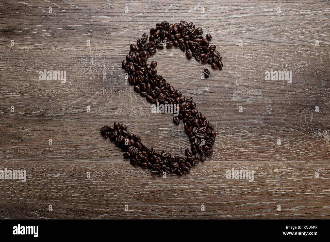 Dark roasted coffee bean arranged on a wooden table in the shape of ...