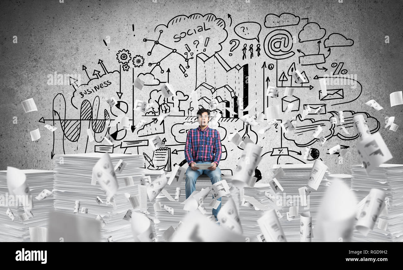 Attractive man sitting on pile of paper documents Stock Photo - Alamy