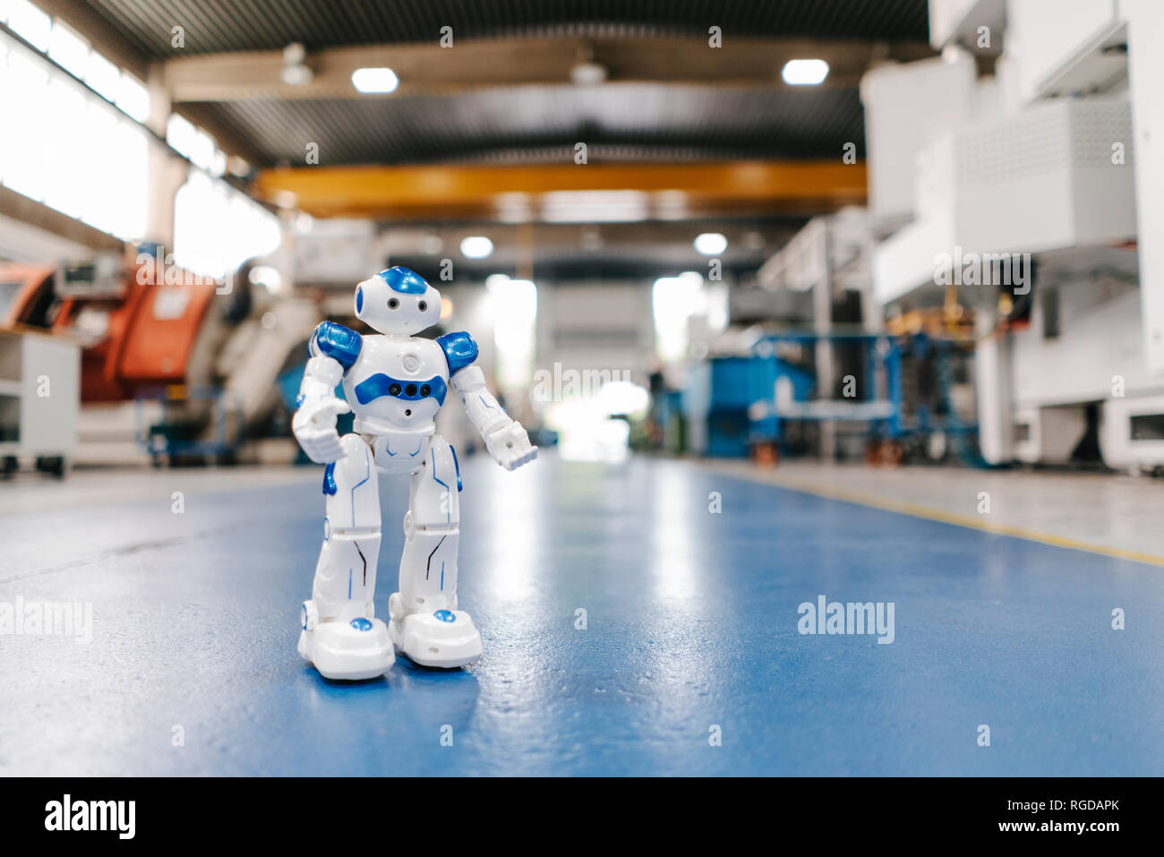 Toy robot standing on floor of factory workshop Stock Photo - Alamy