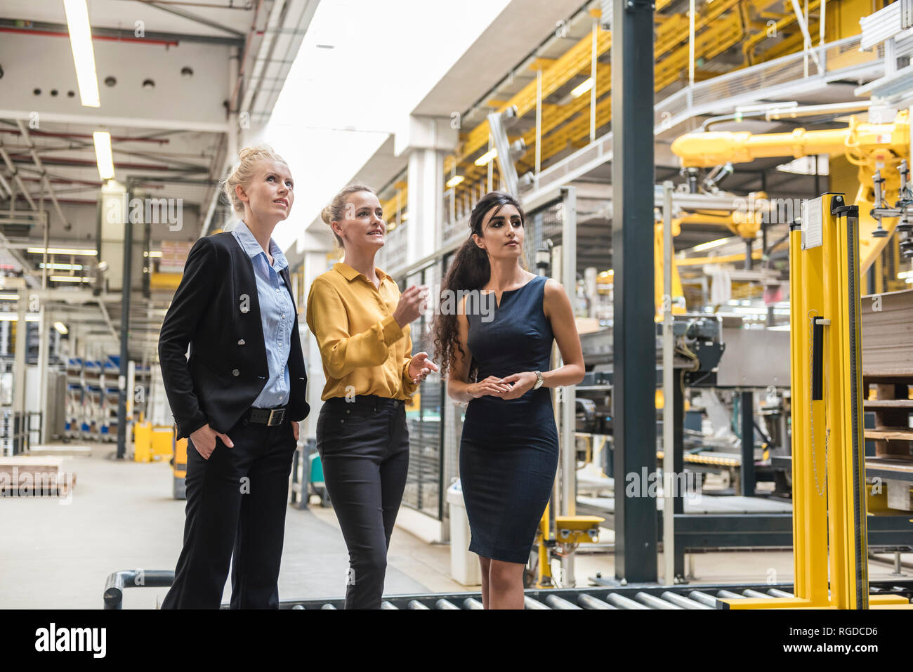 Three women talking in modern factory Stock Photo - Alamy