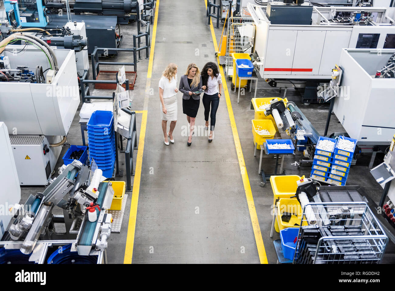 Three women with tablet walking and talking in factory shop floor Stock ...