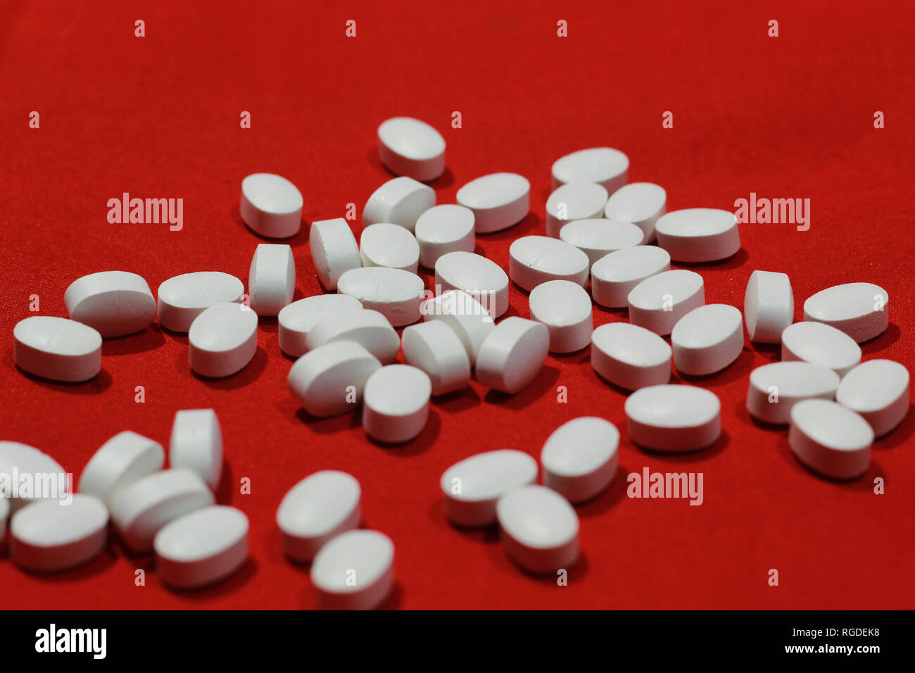 heap of white pill with red isolated background Stock Photo - Alamy