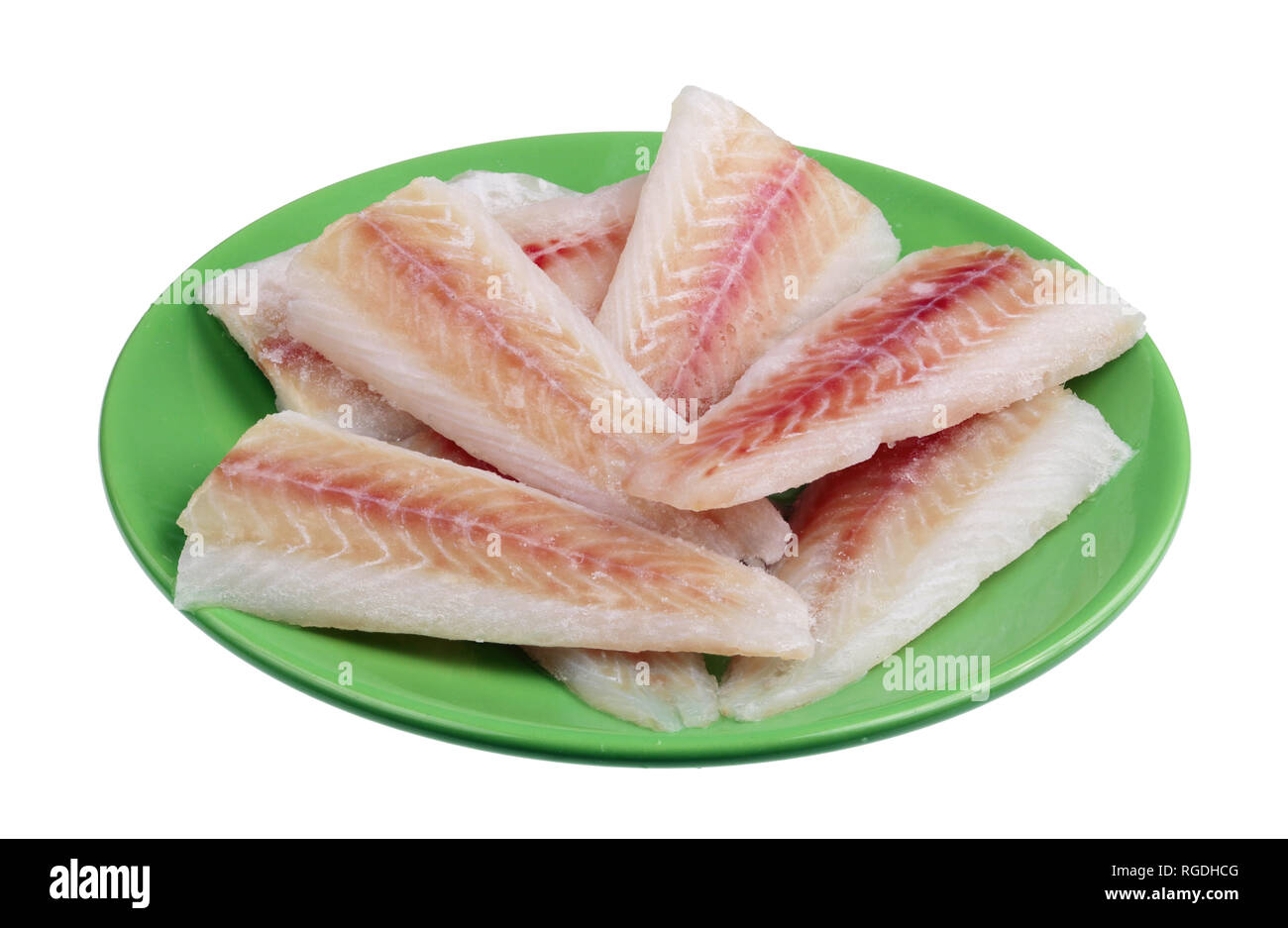 Pieces of frozen atlantic hake fish lying on a green plate isolated ...