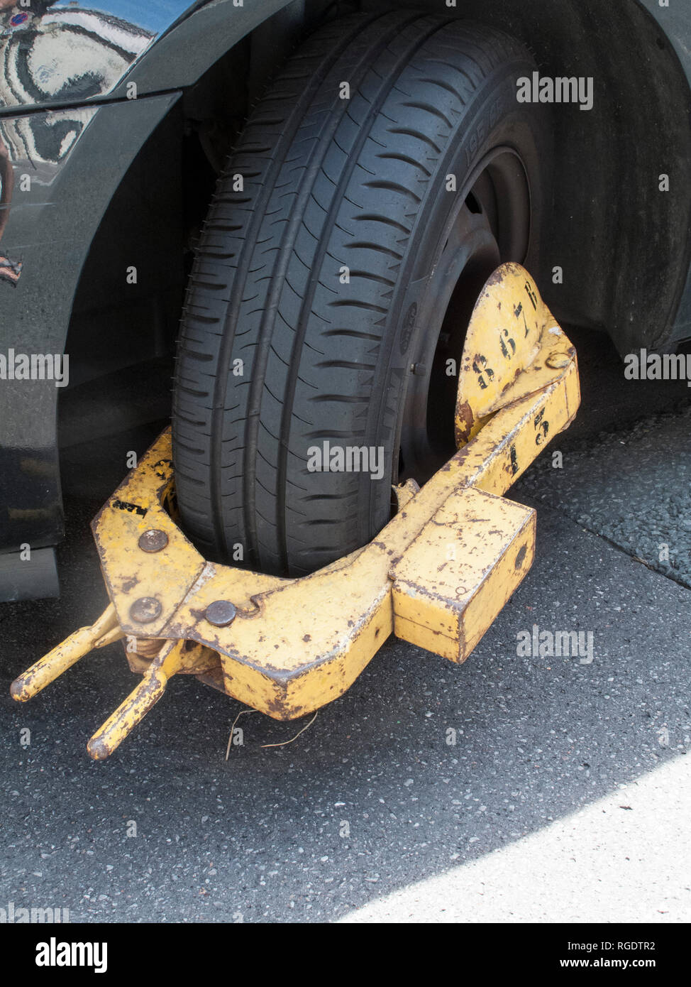 A clamp put on a wheel of a wrongly parked car Stock Photo - Alamy