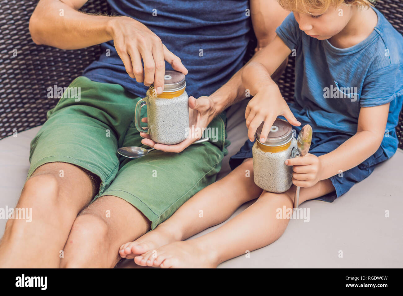 Father and son eat dessert with chia seeds and mangoes by the pool in ...