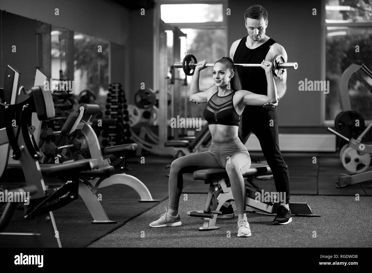Black and white indoor of two people in gym training together. Slim ...