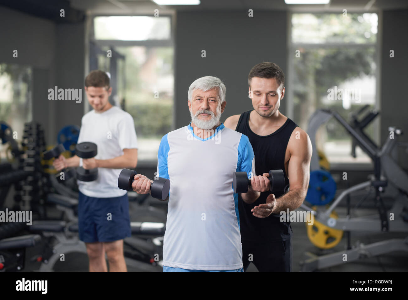 Fit and healthy old man working out with personal trainer in gym ...