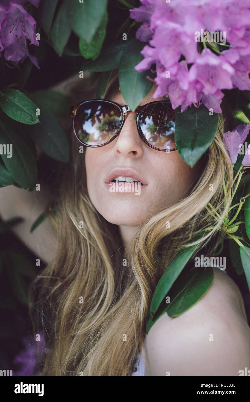 beautiful young girl in a white dress posing in a green bush with pink ...