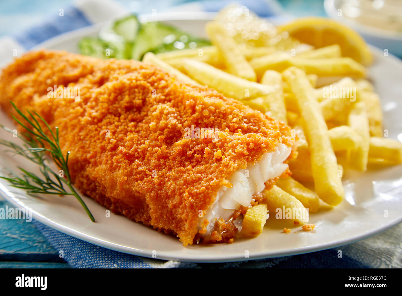 Portion of crispy breaded fish fillet with french fries served on plate ...