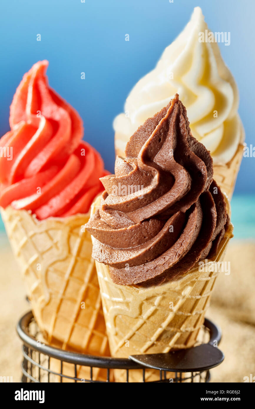 Close up view of colourful ice cream in crispy wafer cones against blue ...