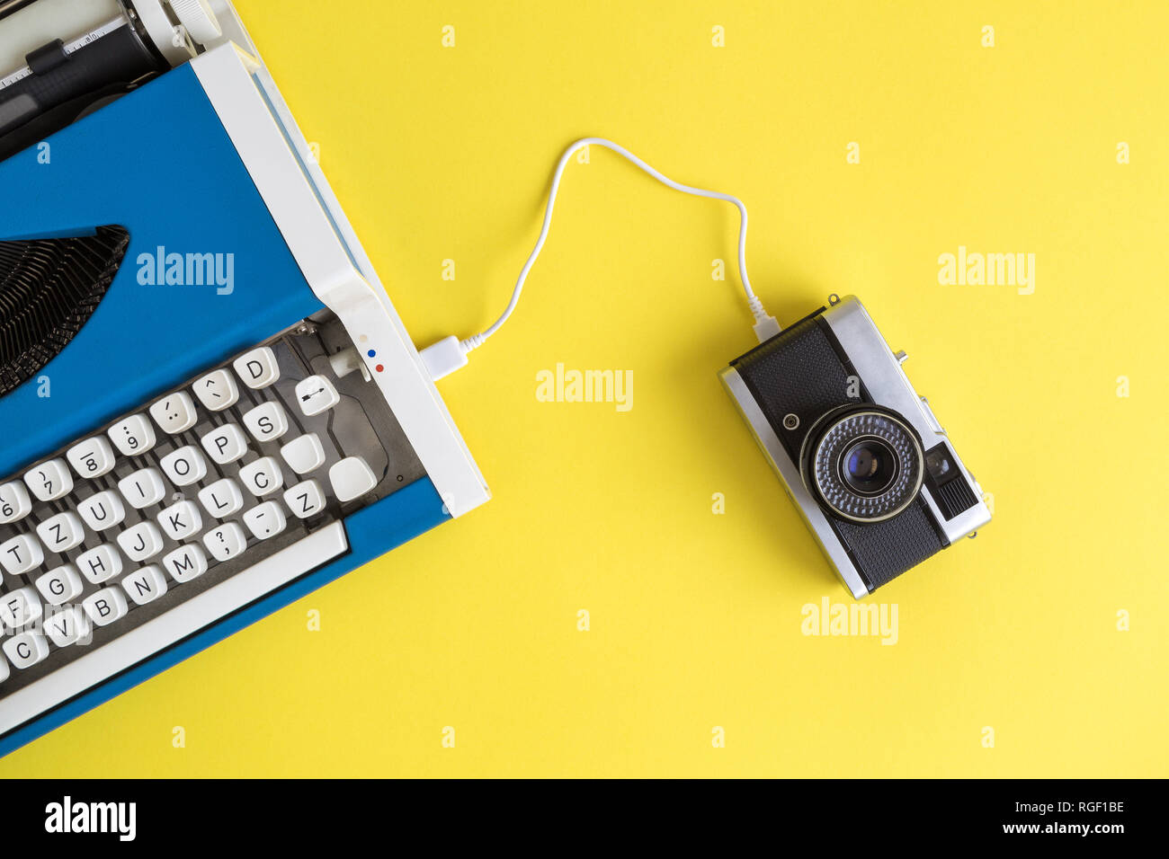 Flat lay of retro typewriter and photo camera connected with cable ...