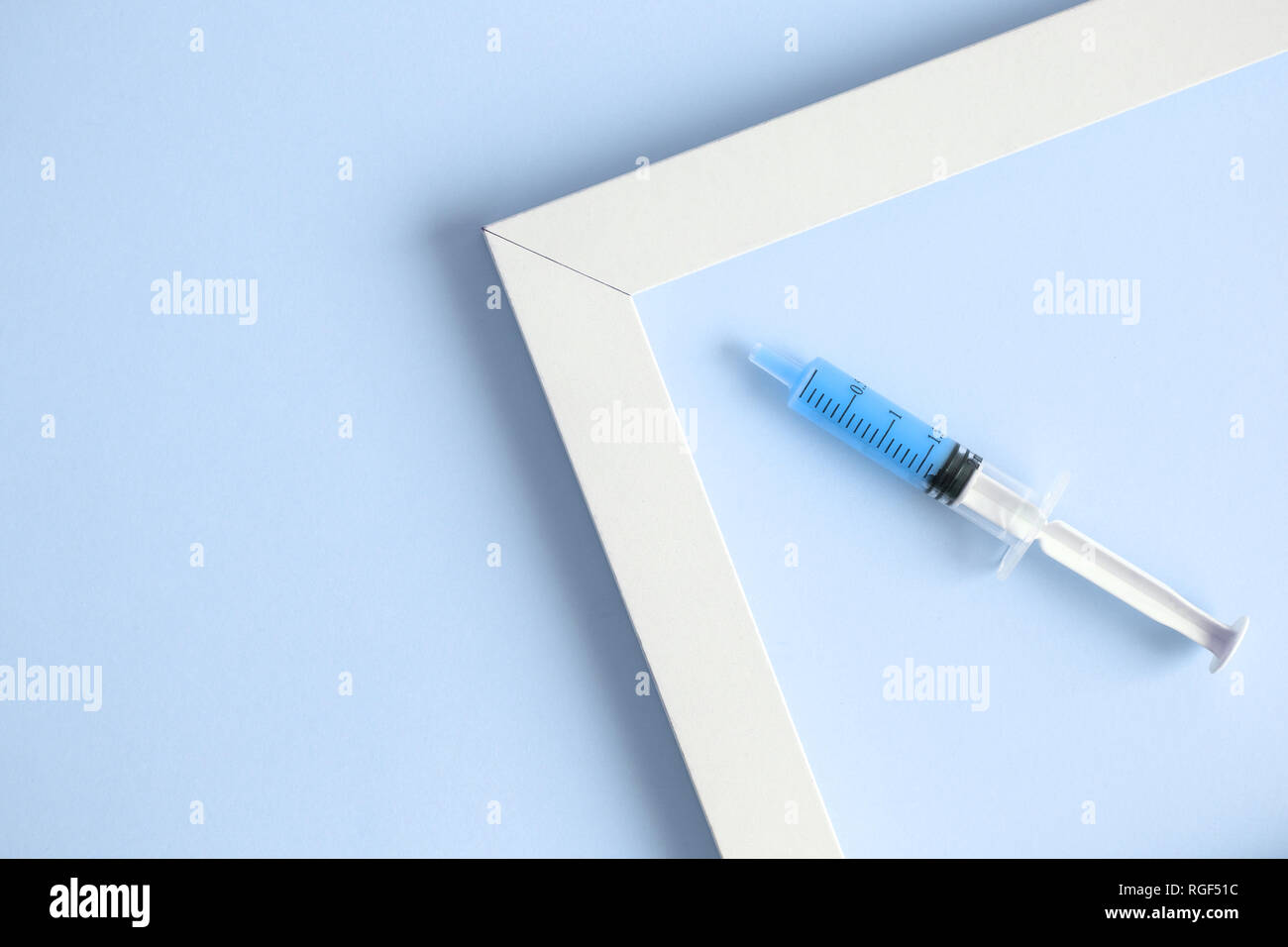Flat lay of syringe and picture frame isolated on blue background ...