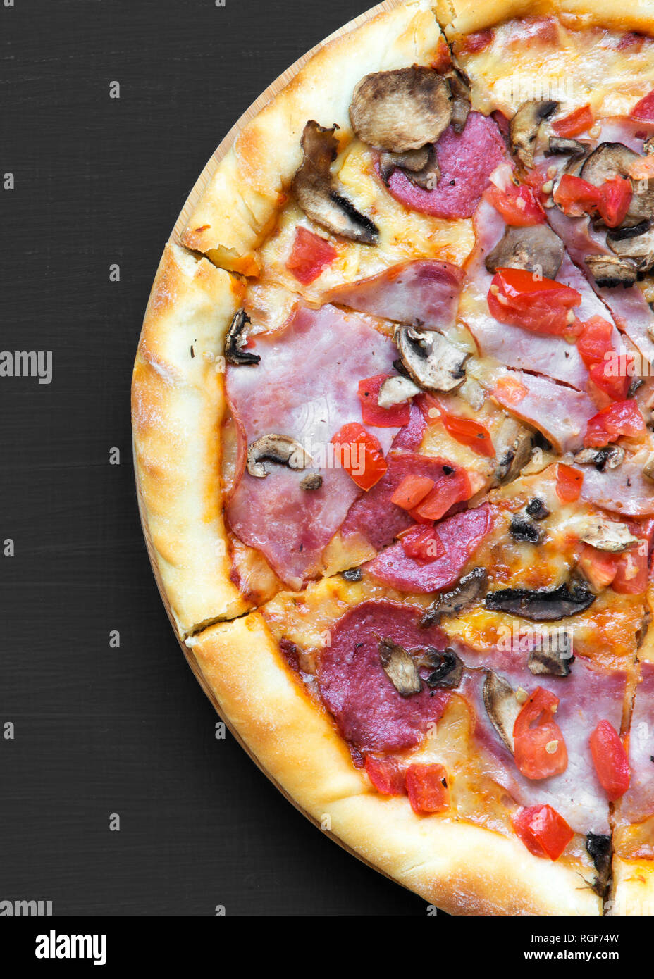 Freshly baked pizza over black surface, overhead view. Flat lay, from ...