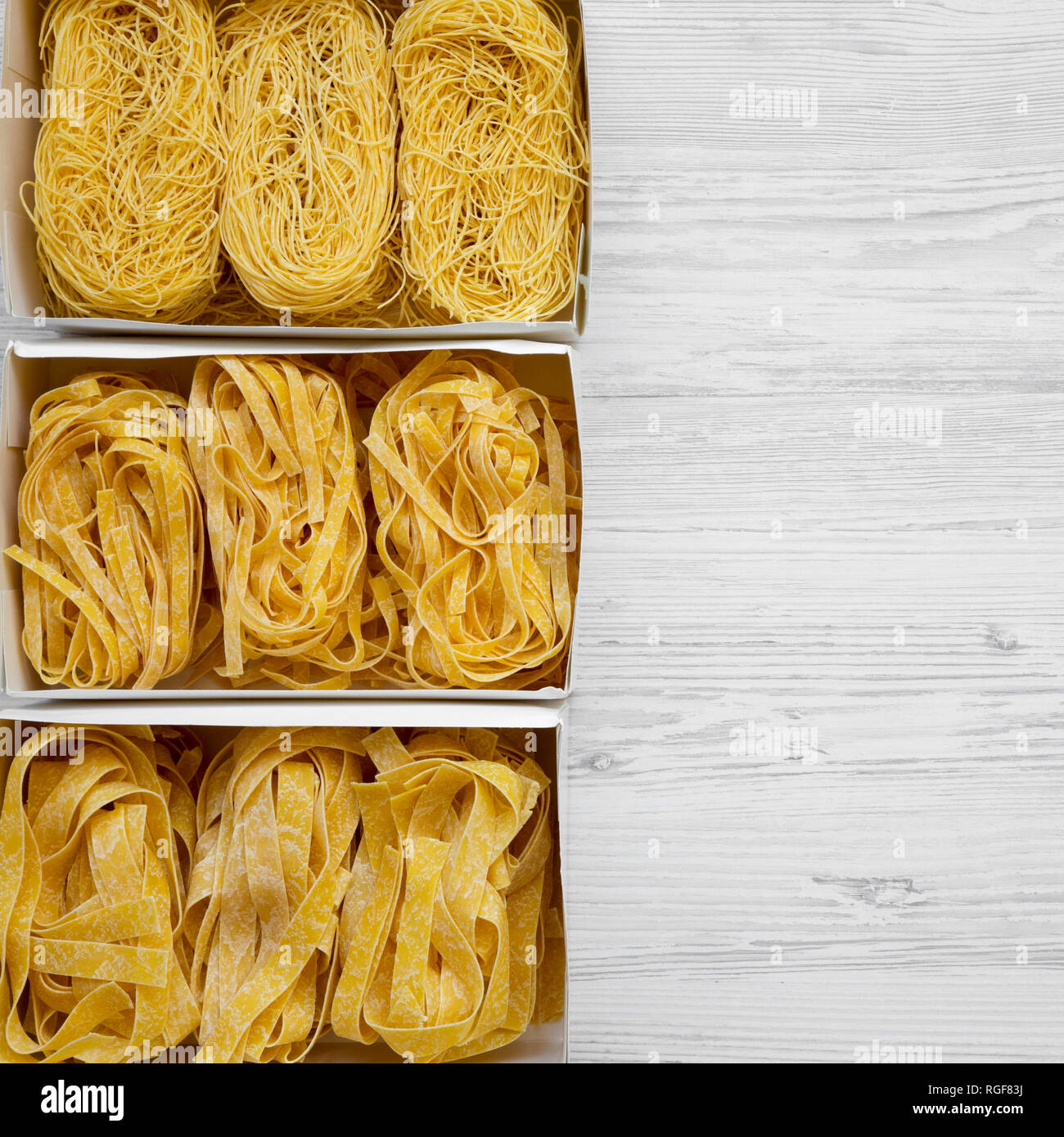 Set of different uncooked pasta in paper boxes over white wooden ...