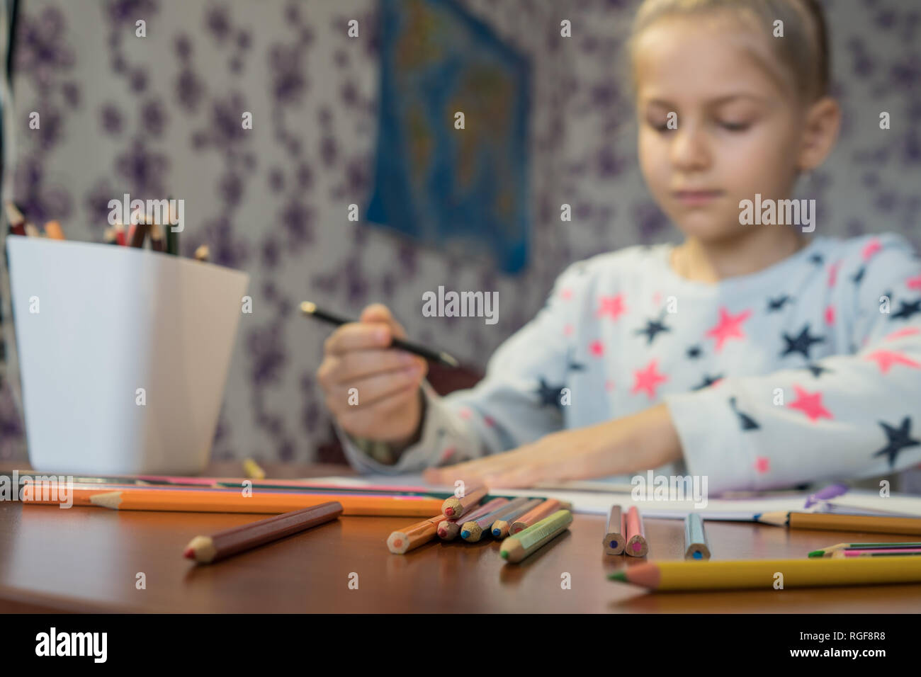 Attentive child writes with crayons on the album. Homework. Children's ...