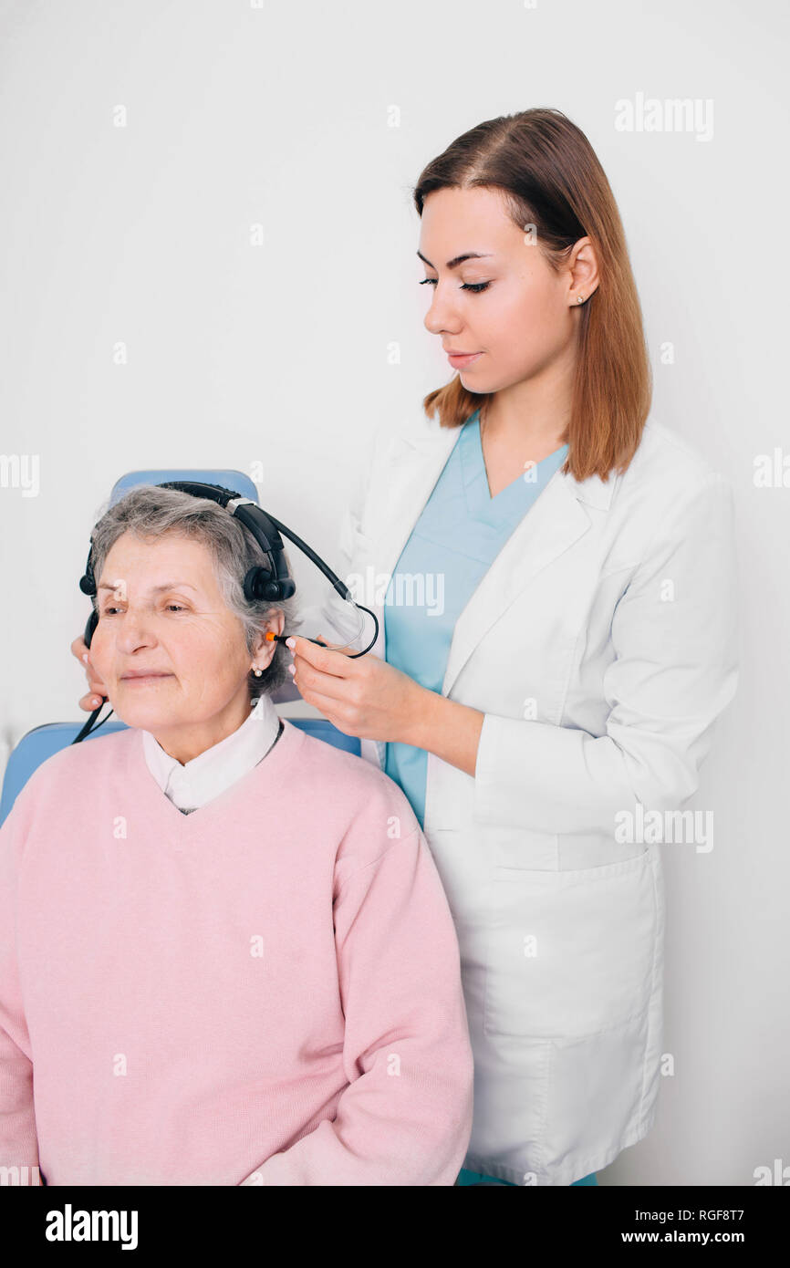 Audiologist doing hearing exam with special headphones to a aged ...