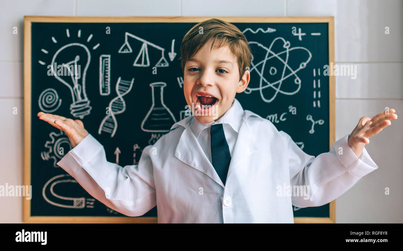 Happy child dressed as a scientist in front of chalkboard with drawings ...