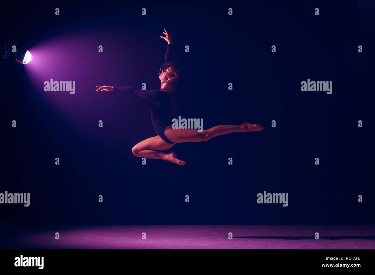 Young female ballet dancer dancing on neon lights studio background ...