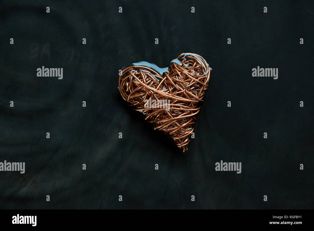 Copper wire heart made from reclaimed electric cable. Surrounding water ...