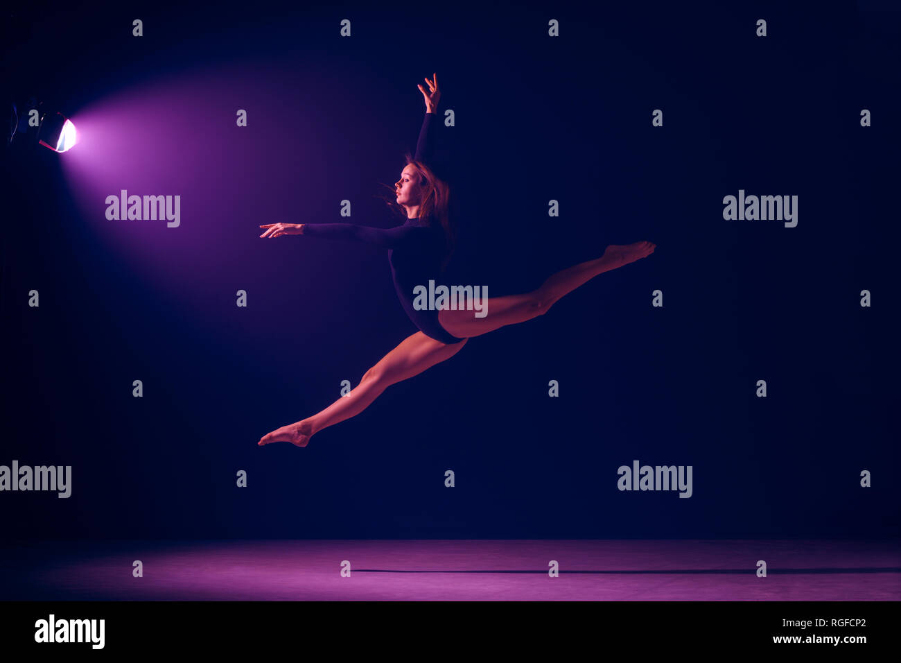 Young female ballet dancer dancing on neon lights studio background ...