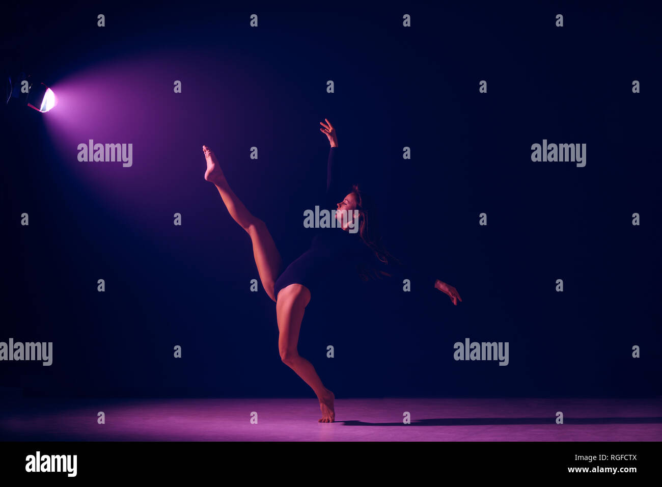 Young female ballet dancer dancing on neon lights studio background ...